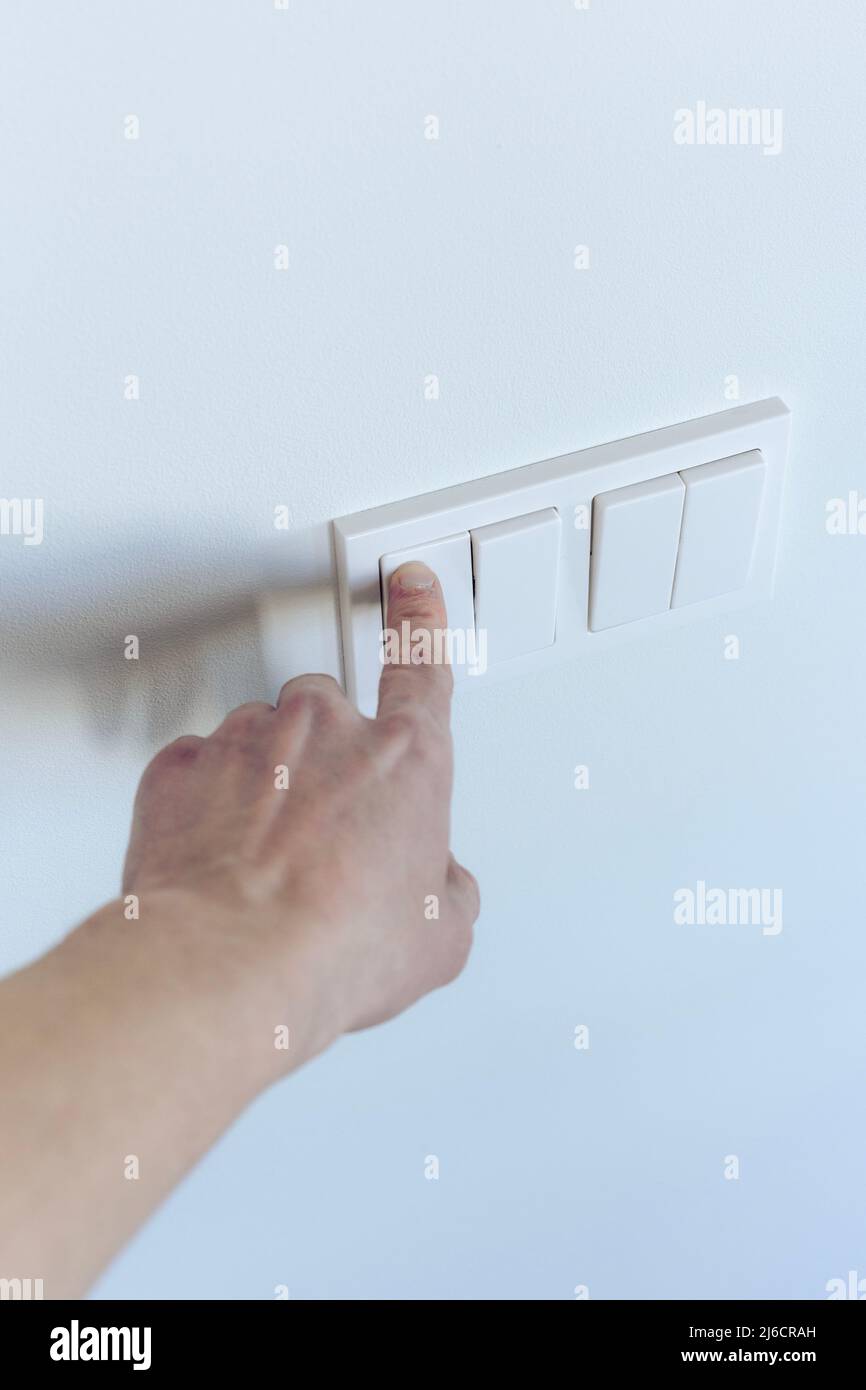 Hand presses a light switch with a finger Stock Photo - Alamy