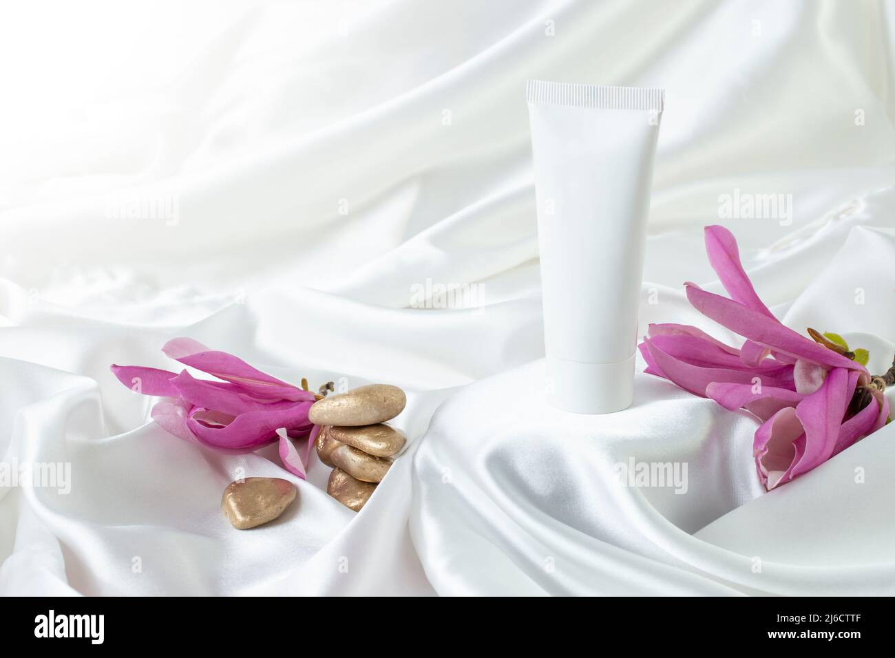 Cream tube next to magnolia flowers, cosmetic product display on white ...