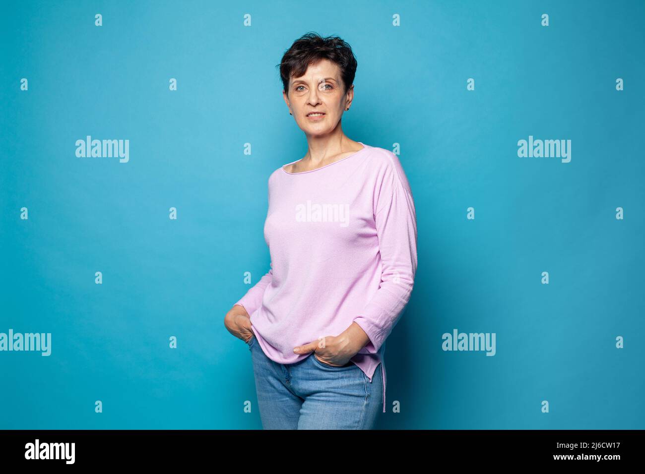 Portrait of attractive mature woman 55 years old on blue background ...