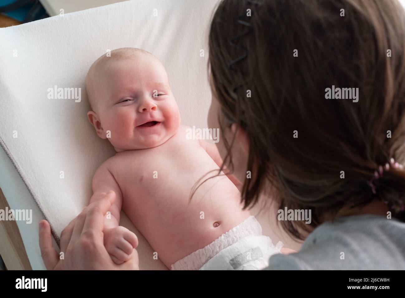 Caucasian baby looking on his mother smiling. Cuddling spending time ...