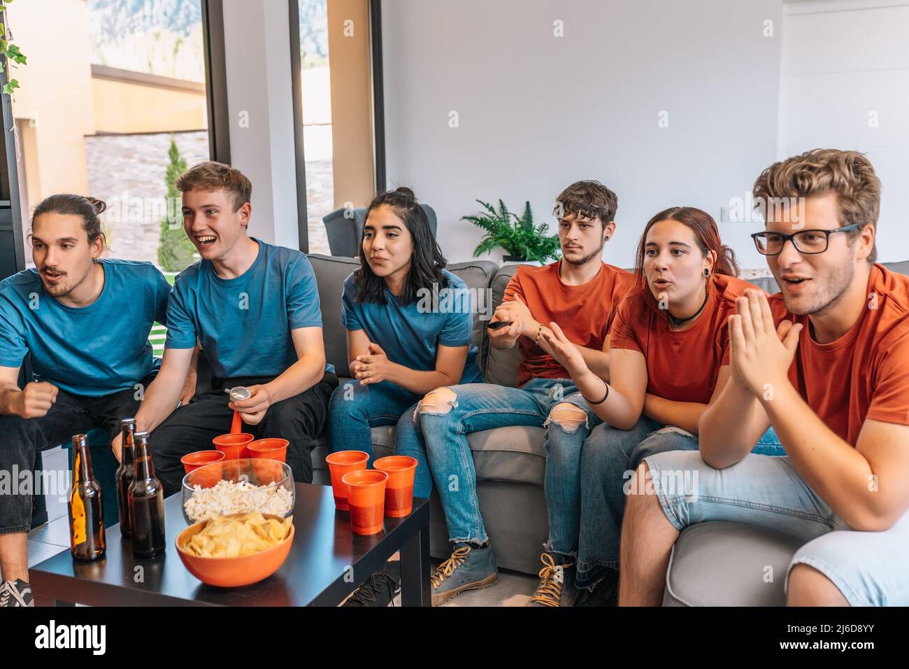 happy friends watching a football event on TV, one of them unexpectedly ...