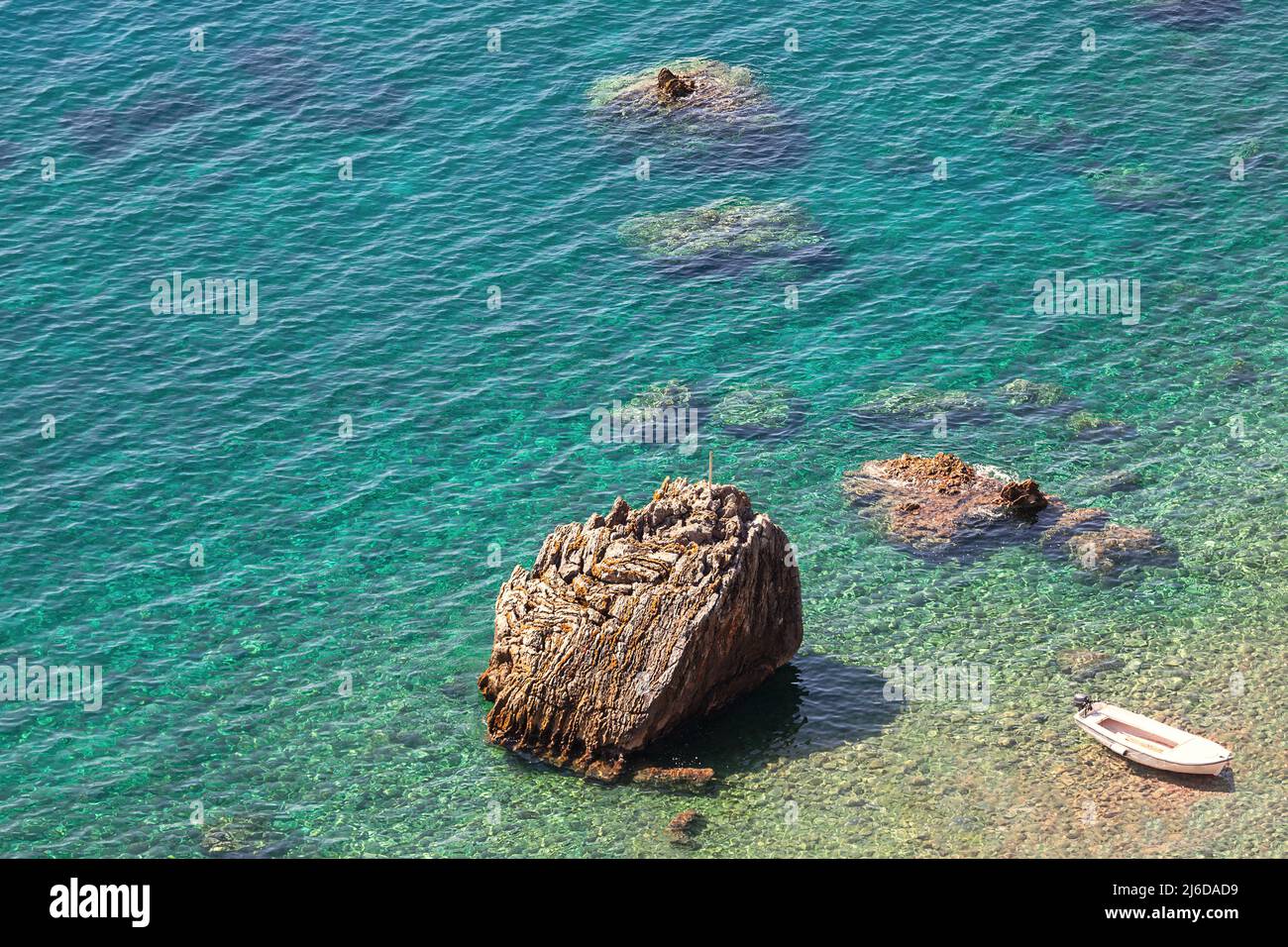 Boat in a blue water near island rocks Stock Photo - Alamy