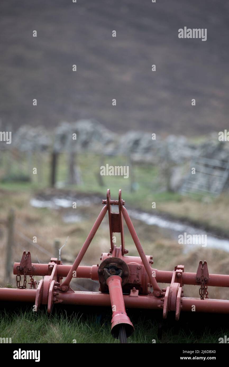 Red farm machine in the rugged landscape of the Isle of Lewis in April ...