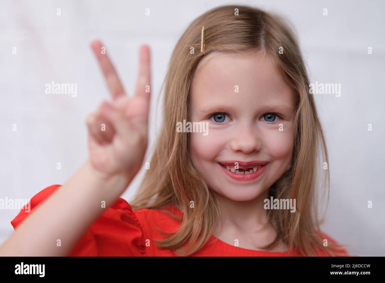 Smiling little girl without front teeth gesture two fingers up Stock ...