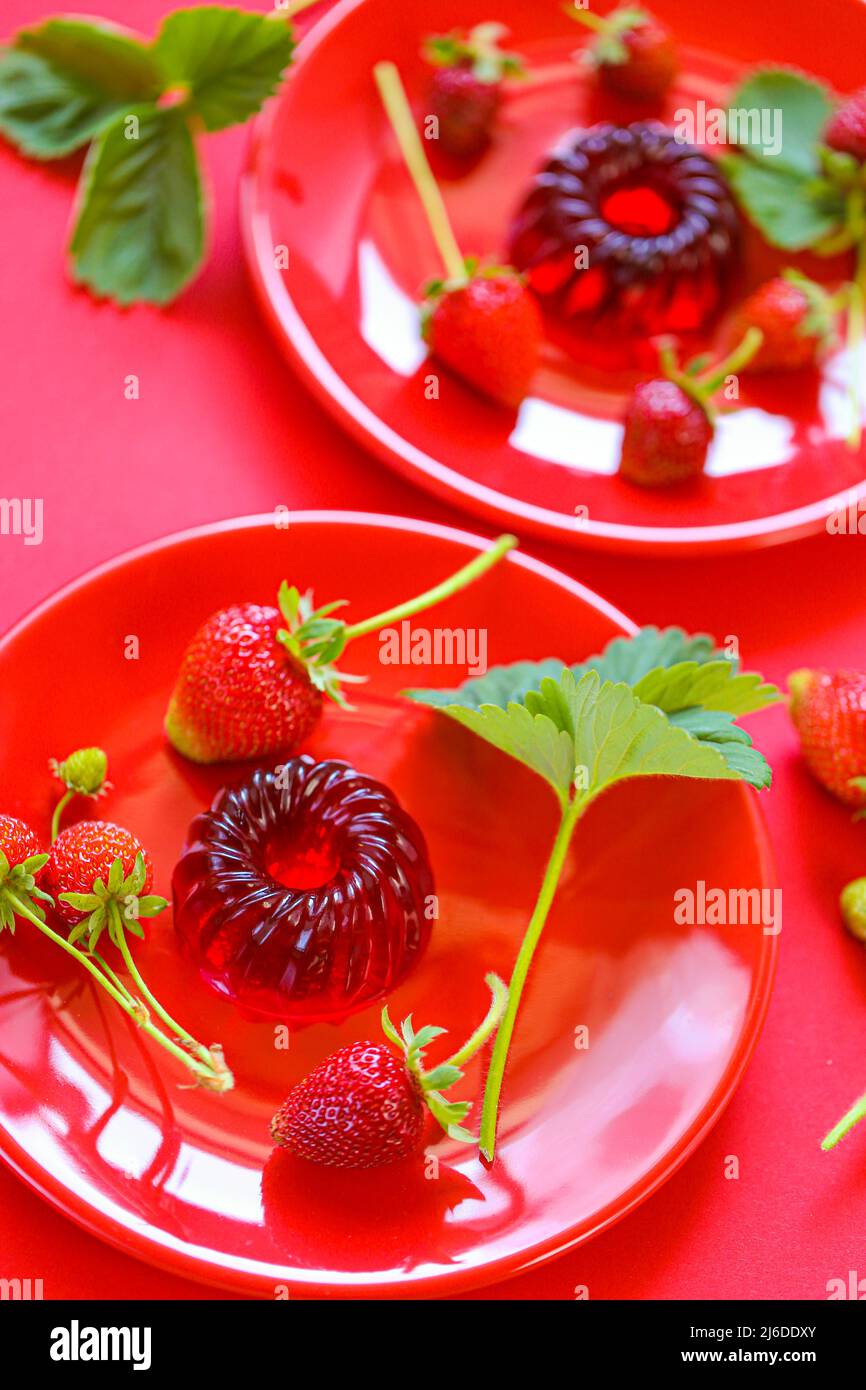 Red jelly and strawberries with leaves on a red plate on a Red ...