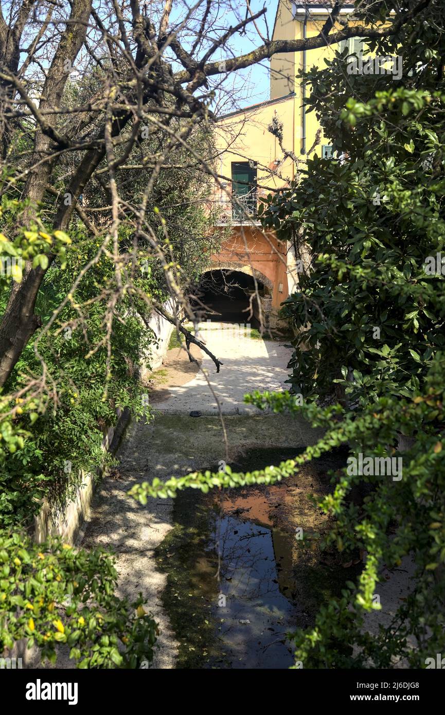 Facade of a country house with a dry stream of water passing beneath it ...