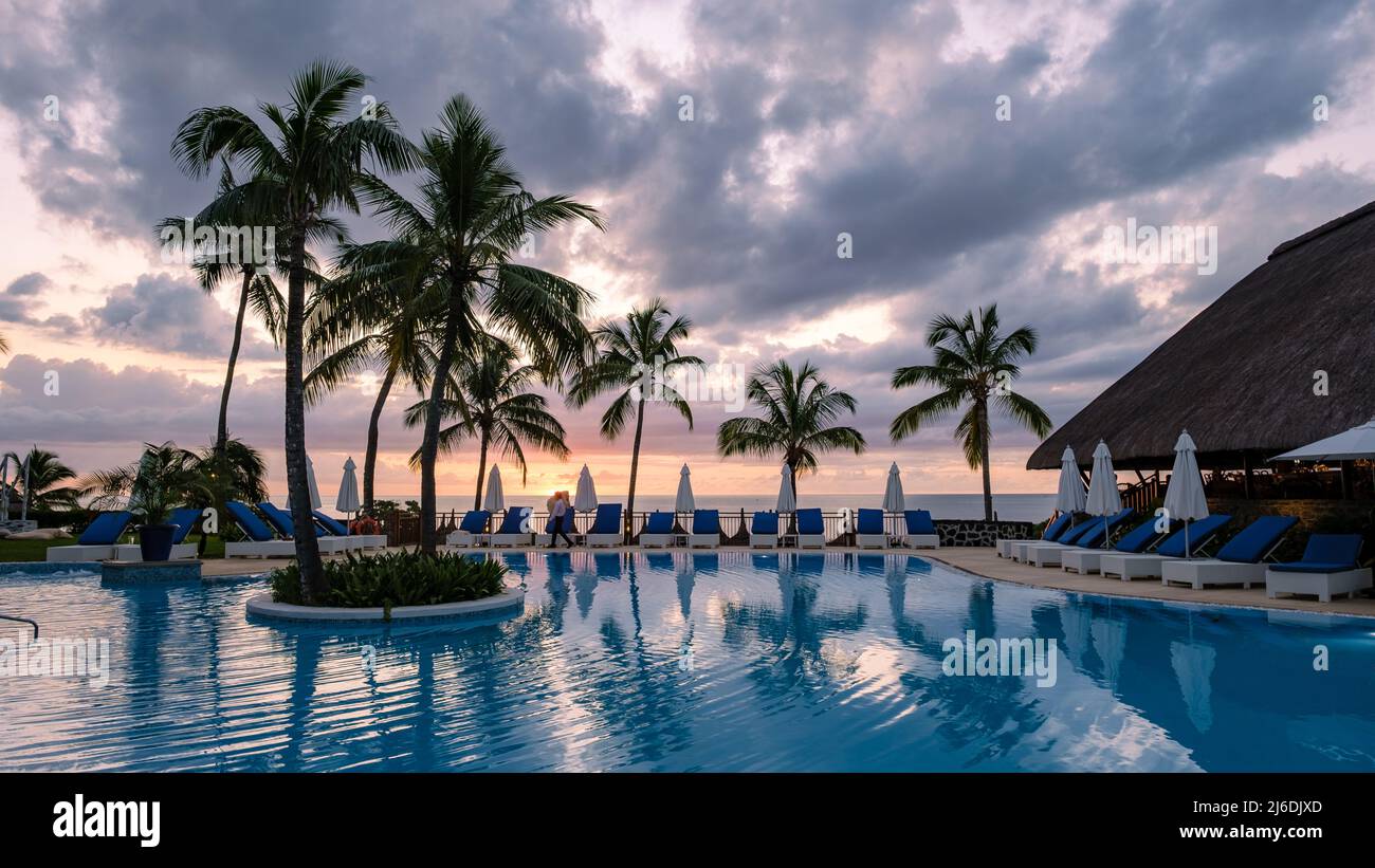 sunset by a swimming pool with tropical palm trees during a luxury vacation holiday Stock Photo ...