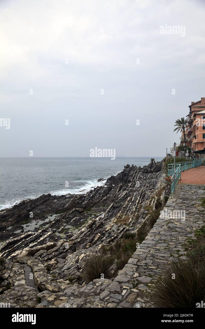 Paved trail on a cliff with buildings by the sea on a cloudy and rainy ...