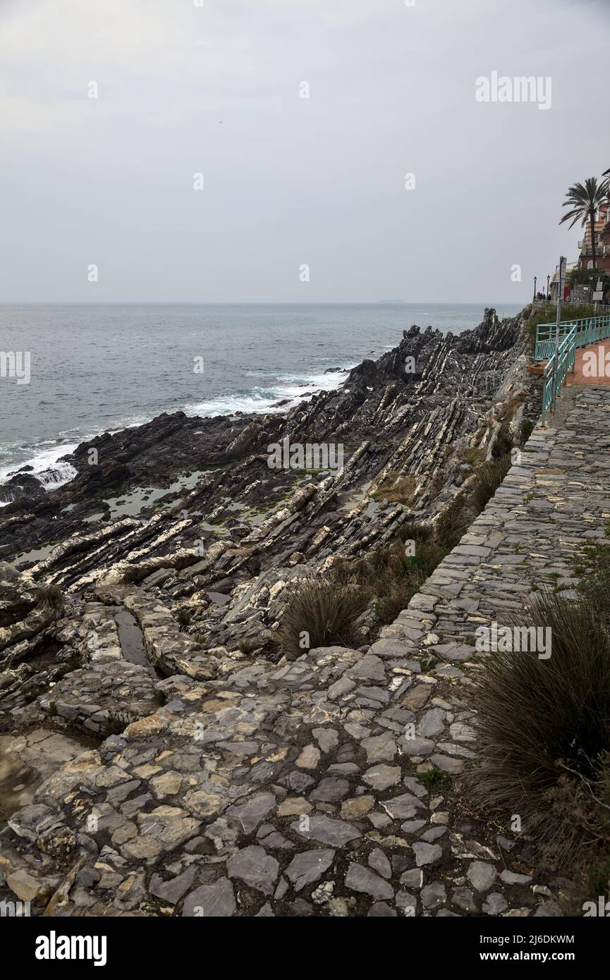 Paved trail on a cliff with buildings by the sea on a cloudy and rainy ...