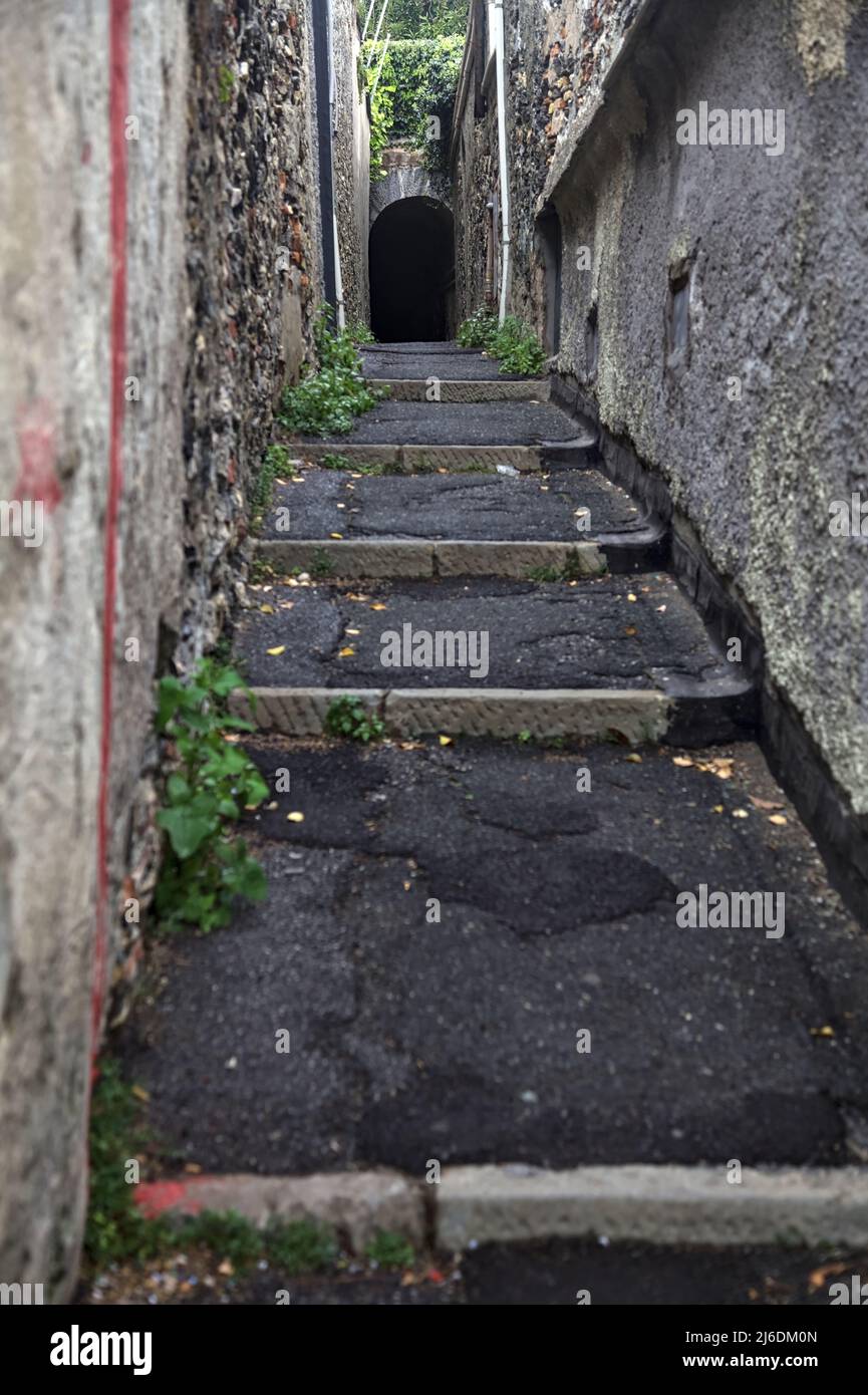 Alley with concrete staircase between buildings that leads to a tunnel ...