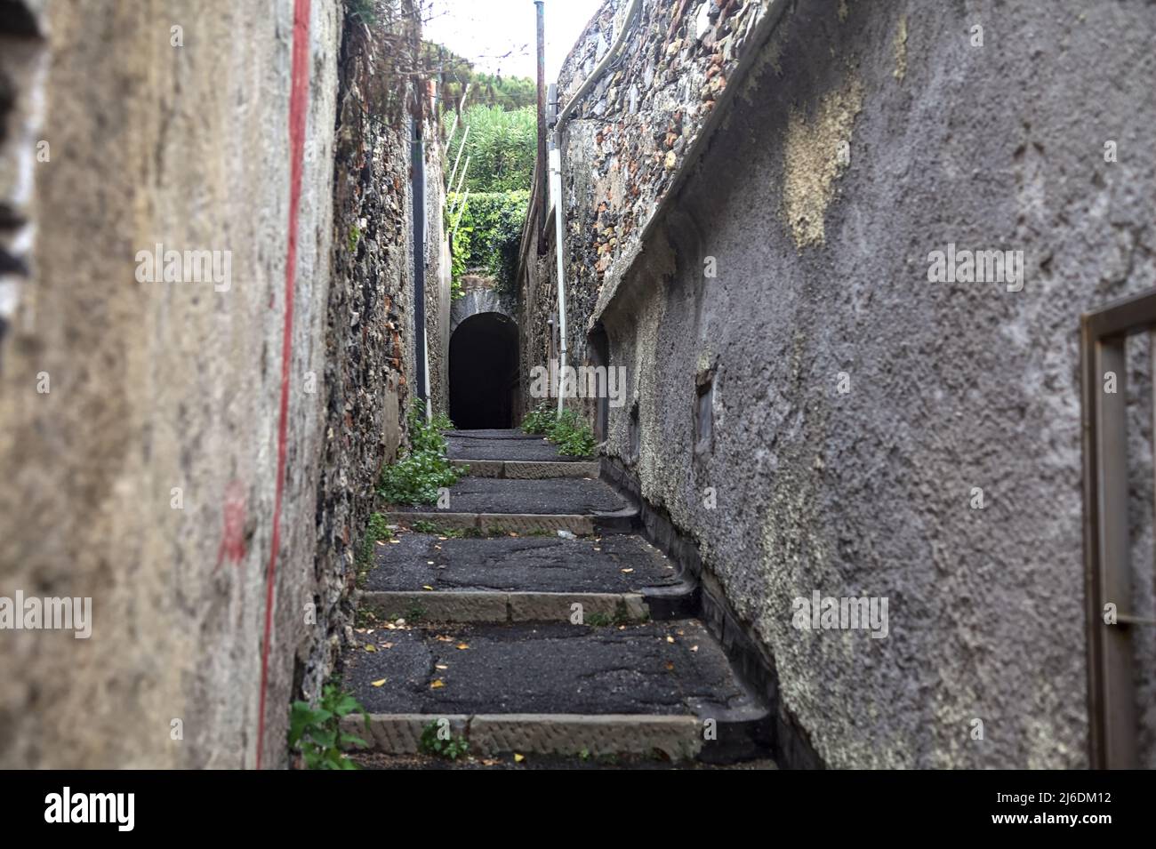 Alley with concrete staircase between buildings that leads to a tunnel ...