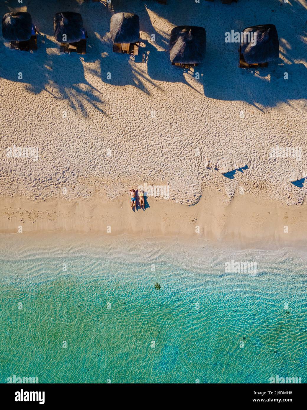 drone aerial view of a tropical beach, men and woman walking a tropical ...