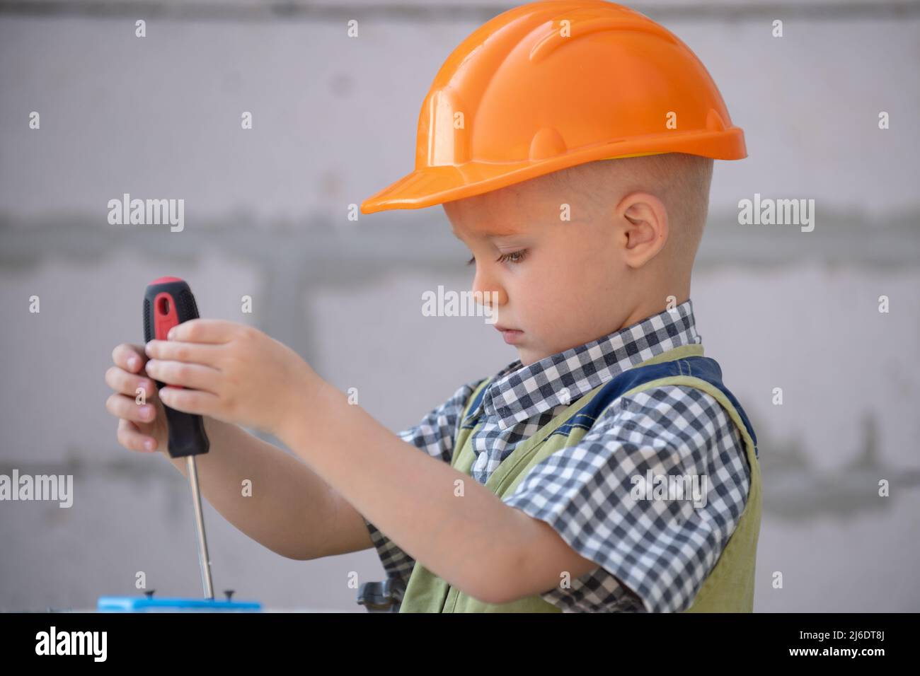 Kid boy twists bolt with screwdriver. Child repairman with repair tool ...