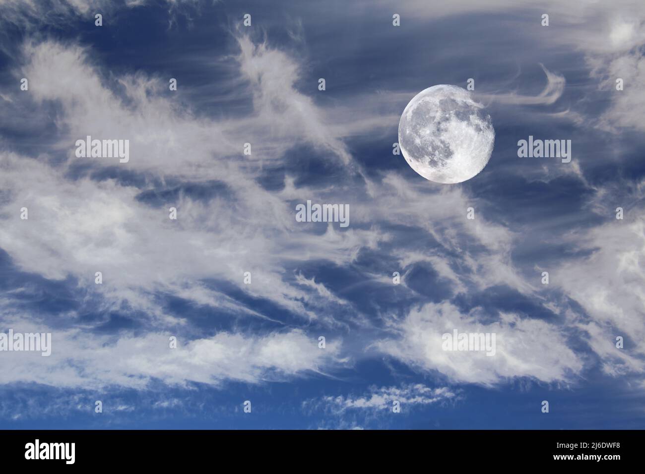 Waning moon on blue sky with cirrus clouds Stock Photo - Alamy