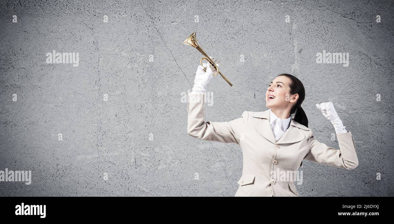 Beautiful woman holding trumpet brass overhead Stock Photo - Alamy