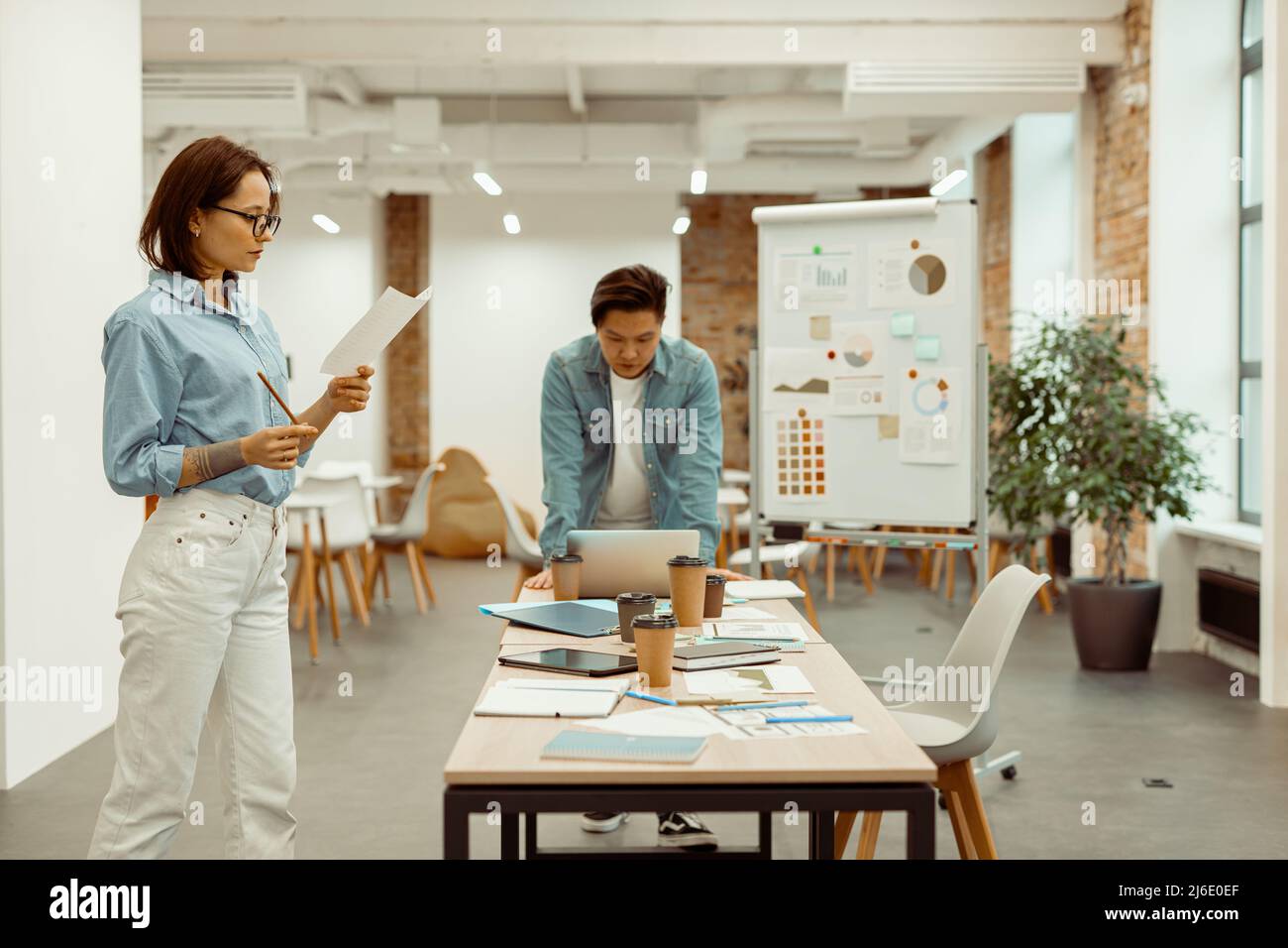 Two colleagues standing in the office and focused on work Stock Photo ...