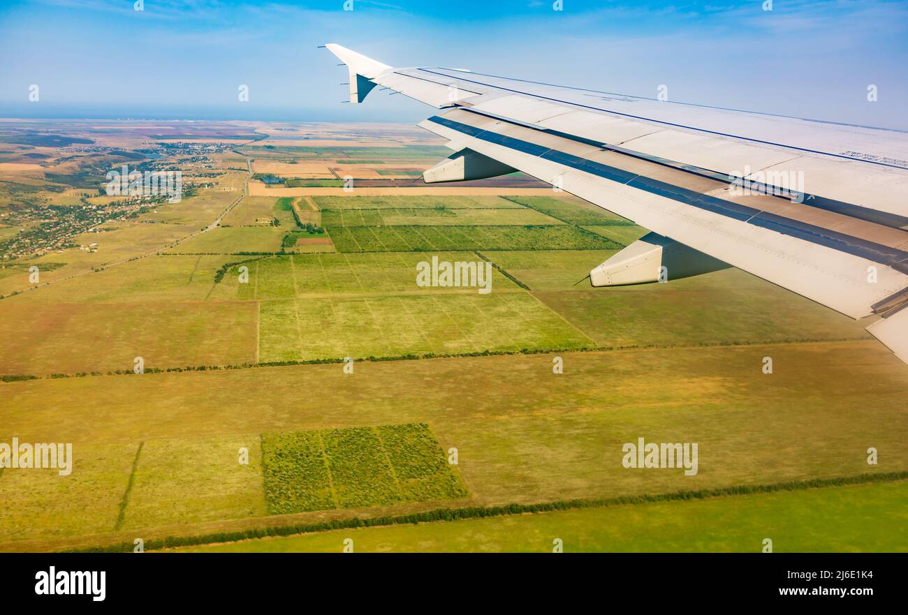 View of airplane wing, blue skies and green land during landing ...