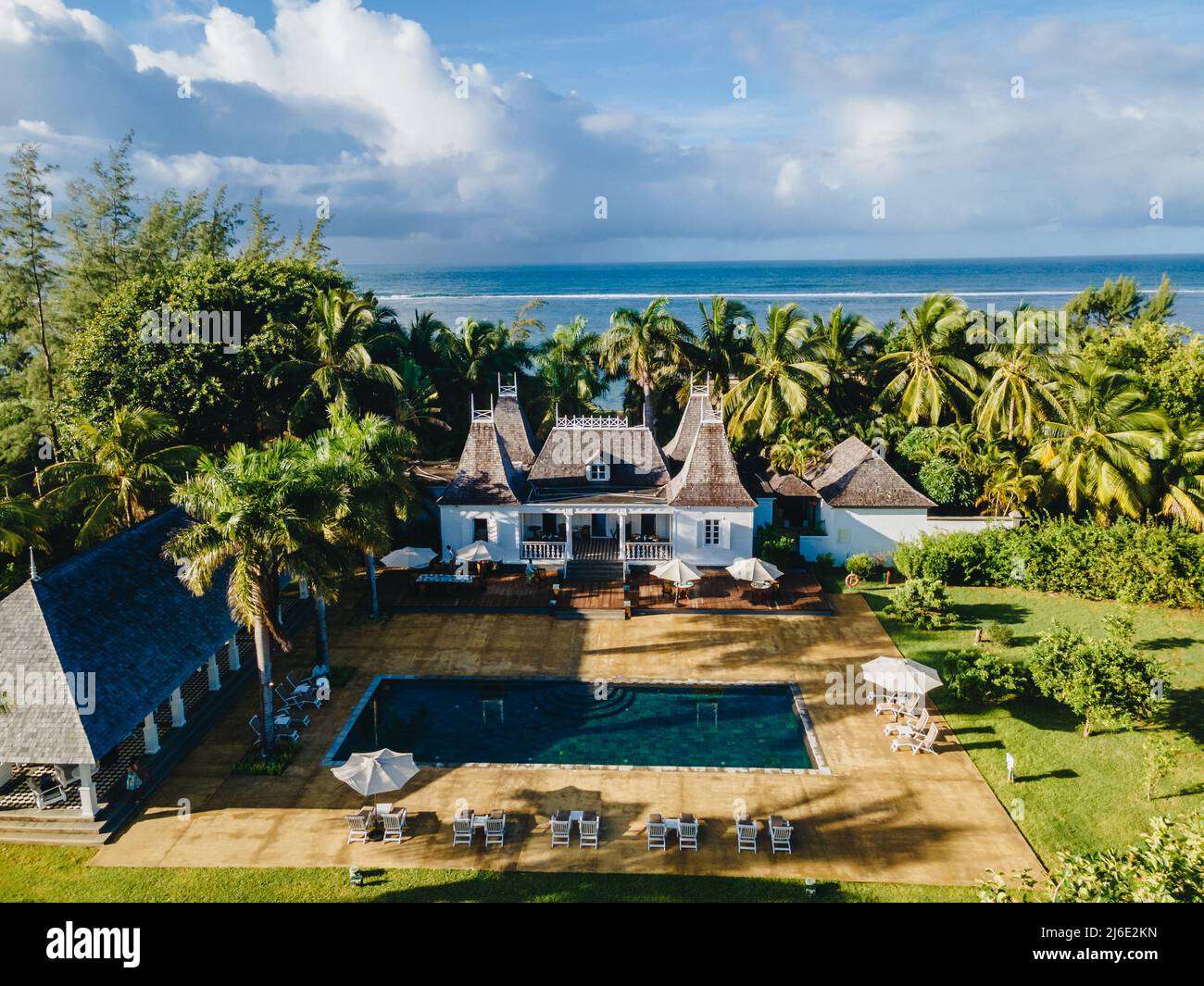 old plantation house with swimming pool and beach chairs by the ocean ...