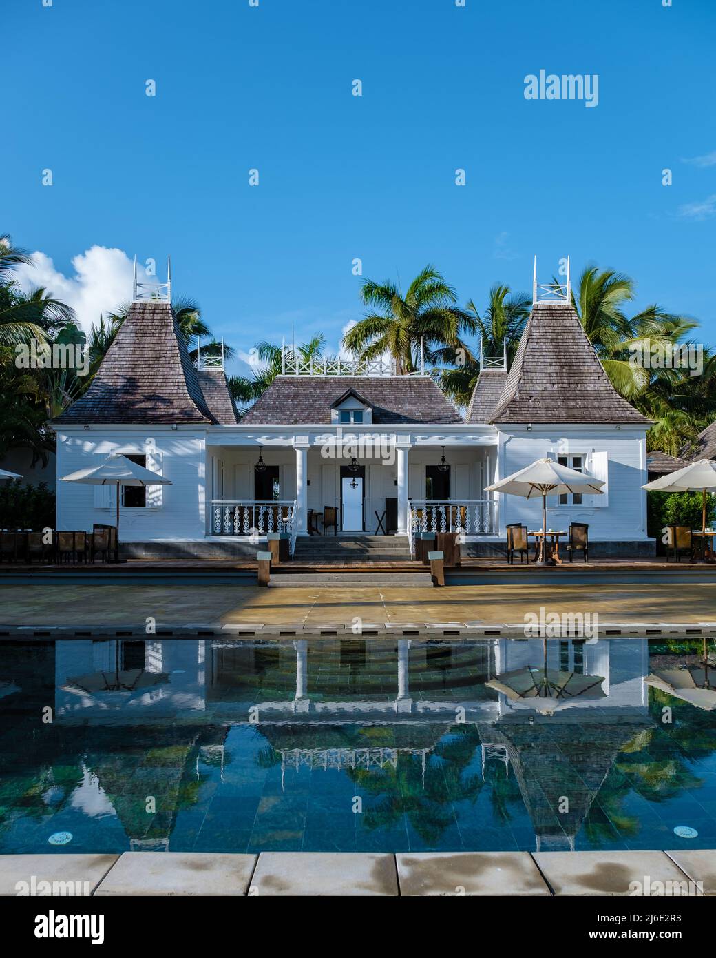 old plantation house with swimming pool and beach chairs by the ocean ...
