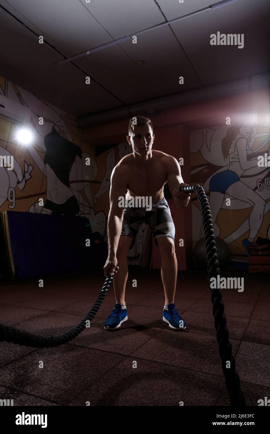 Young man working out with battle ropes at crossfit gym Stock Photo - Alamy