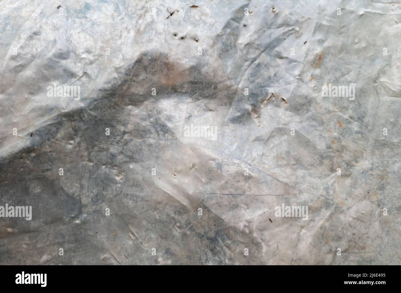 Background from old crumpled dirty polyethylene. Gray streaks and spots ...