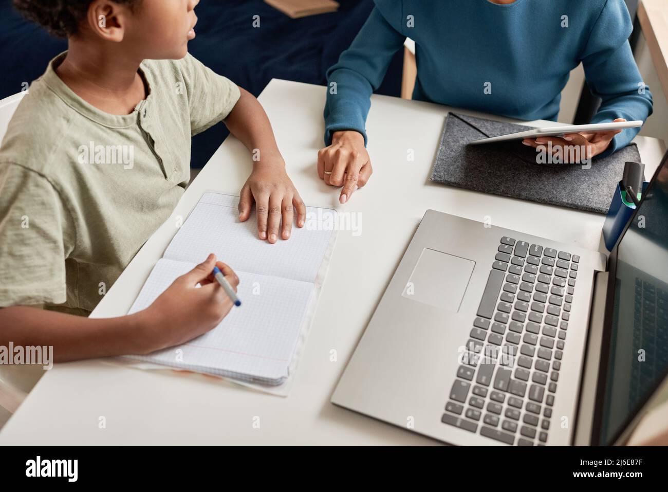 Above view of unrecognizable tutor sitting at table with laptp and ...