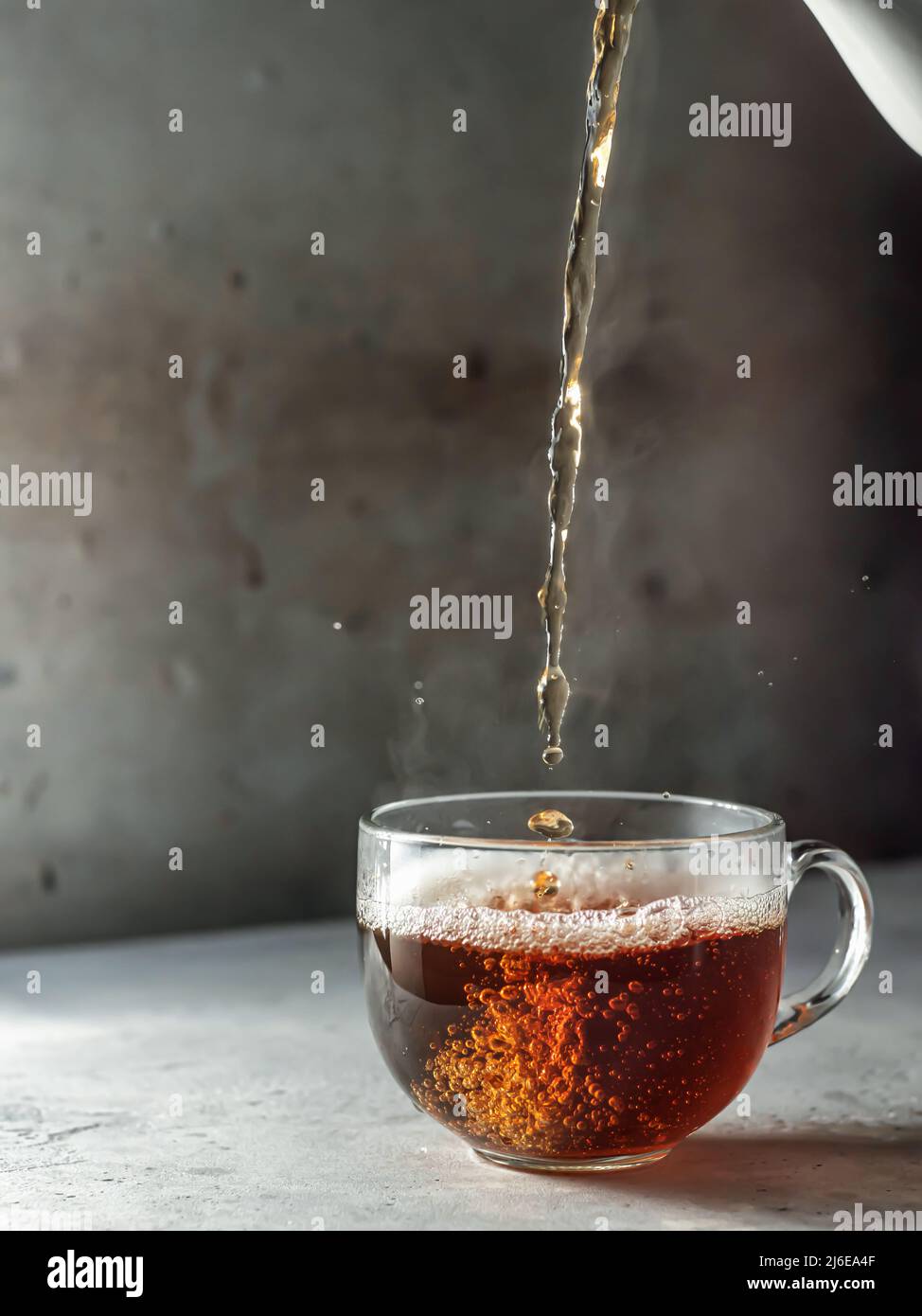 Tea being poured into glass tea cup. Pouring process concept with steam ...
