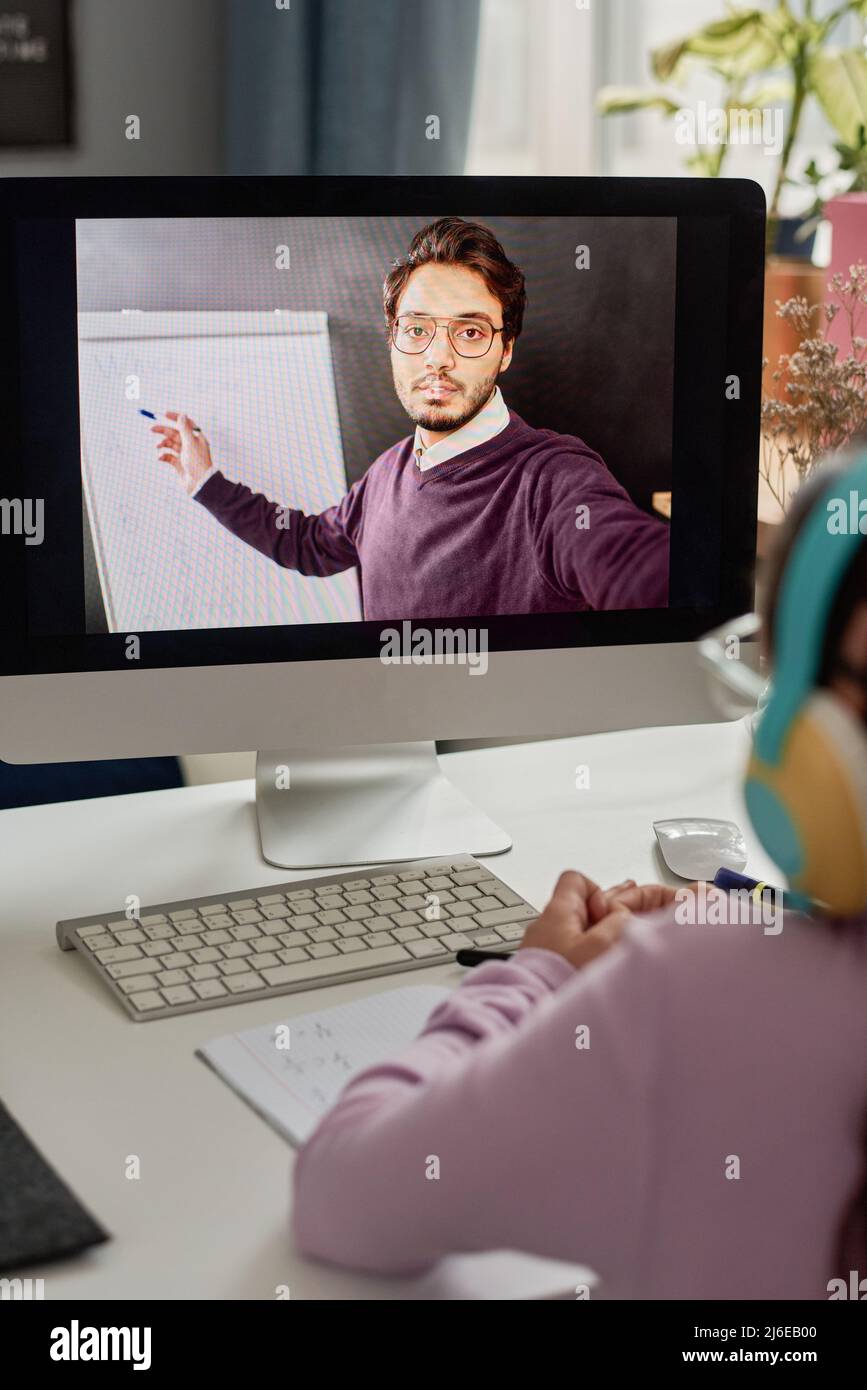 Focus on computer monitor with young middle eastern teacher pointing at ...