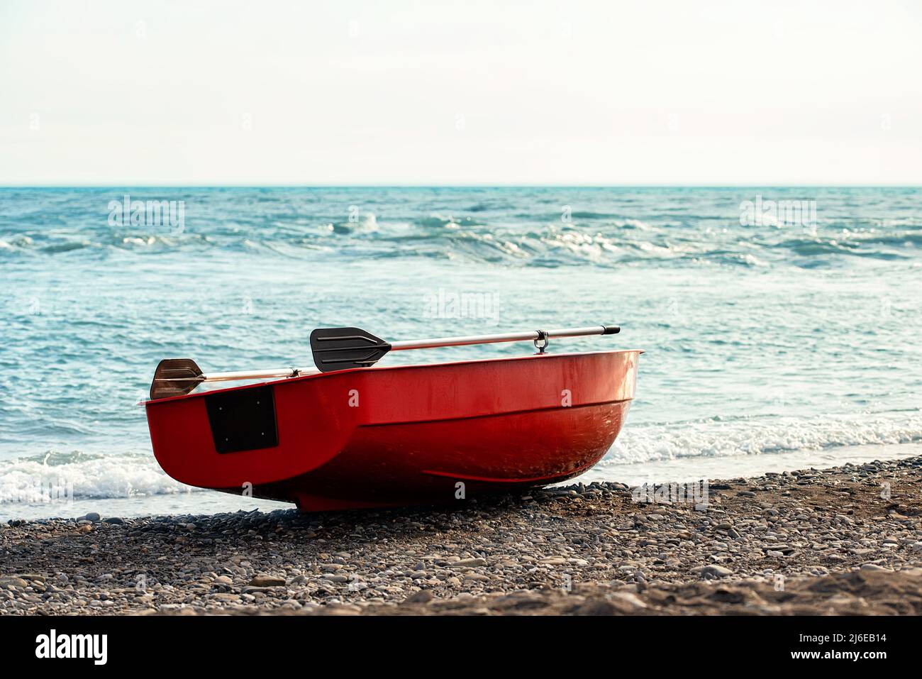 Small red rowboat with sculls lying at shore of the sea Stock Photo - Alamy