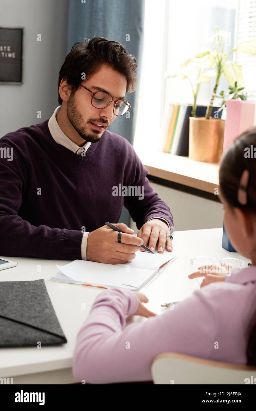 Handsome young mixed race teacher examining solved task made with ... Handsome young mixed race teacher examining solved task made with ...