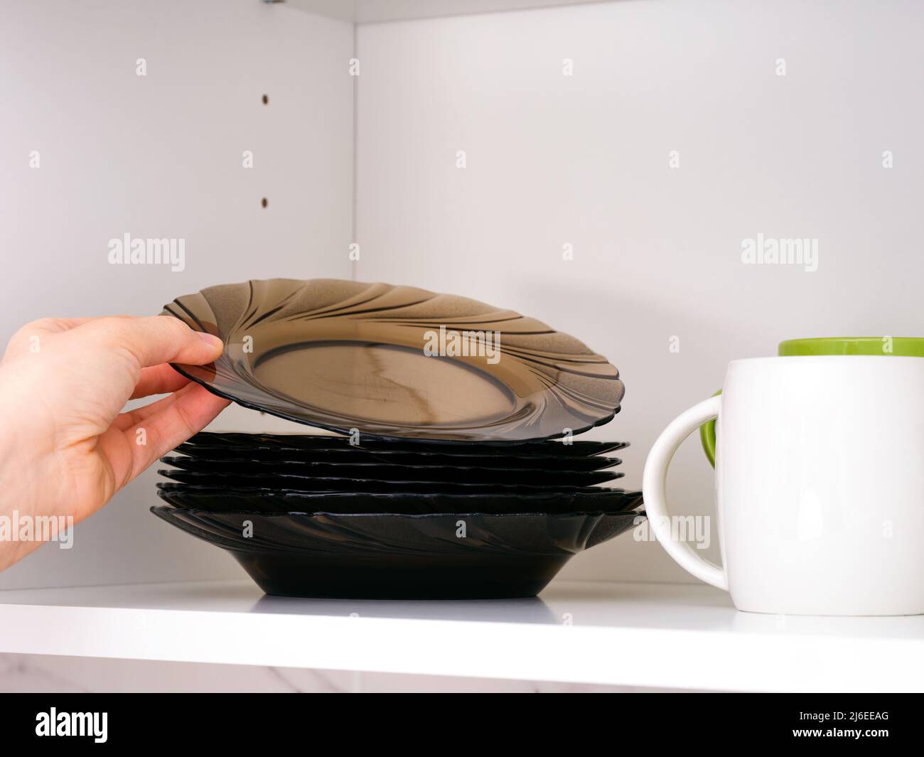 A woman hand taking a plate from a kitchen shelf Stock Photo - Alamy