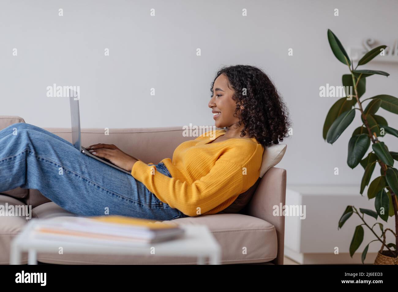 Side view of young African American woman working online via laptop ...