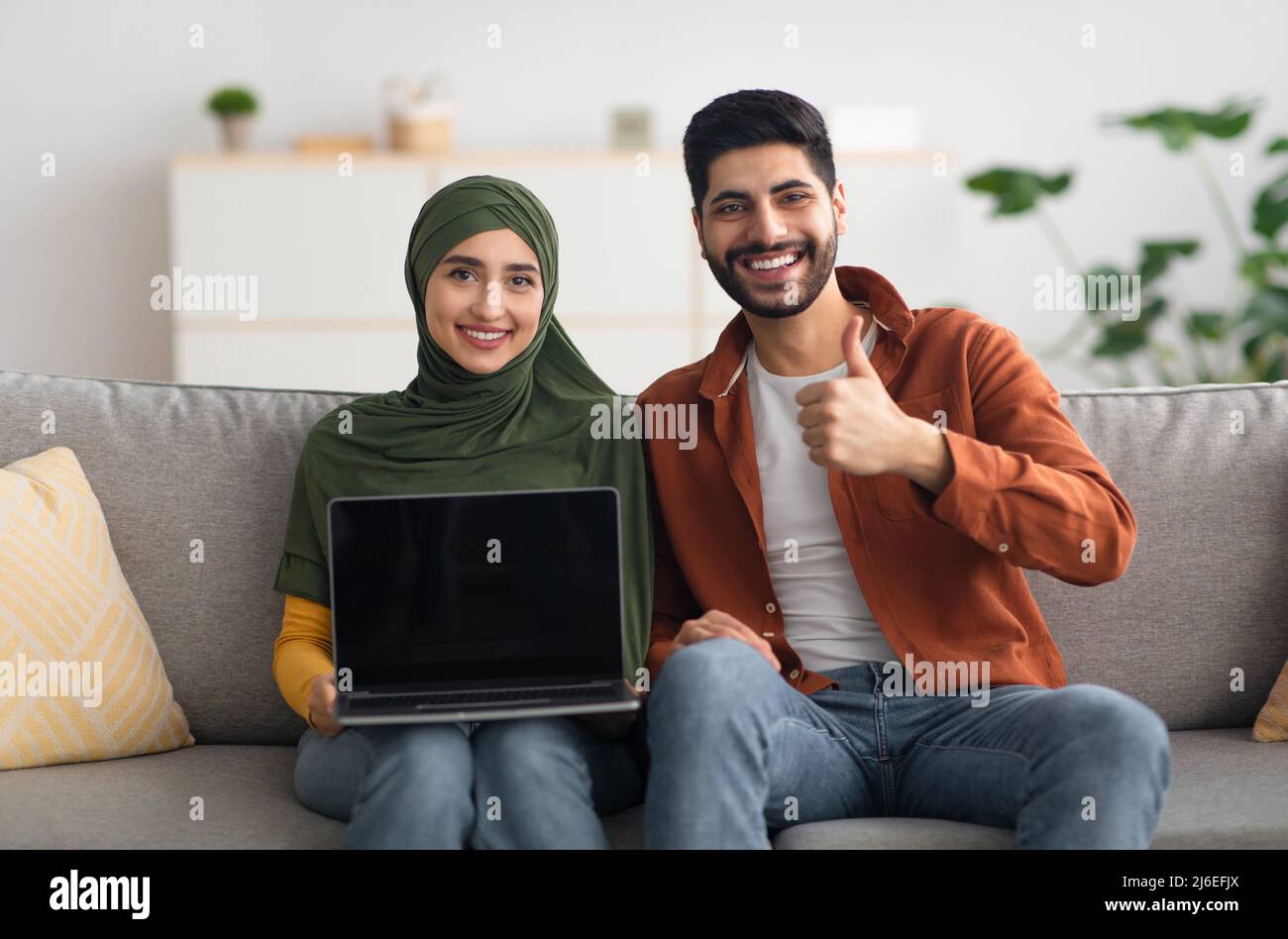 Middle Eastern Couple Showing Laptop Computer With Empty Screen Indoor ...