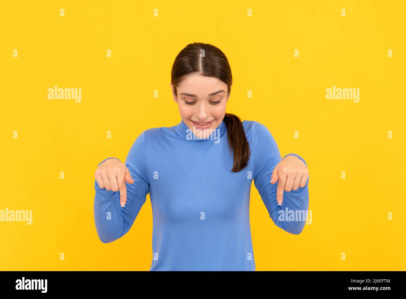 woman portrait pointing fingers down on copy space yellow background ...