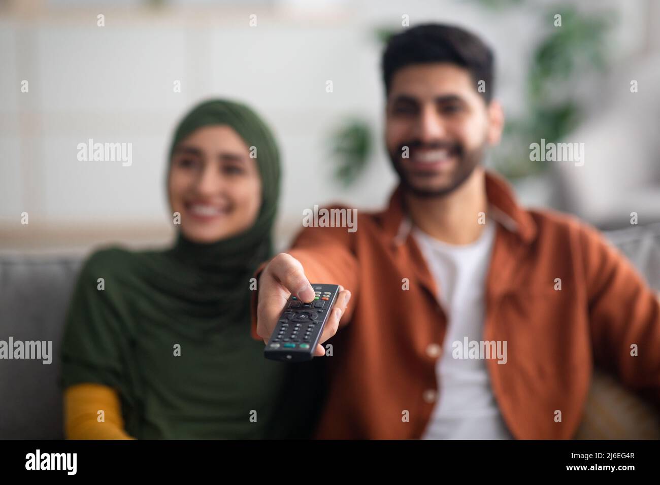 Happy Muslim Family Couple Watching TV Switching Channel At Home Stock ...