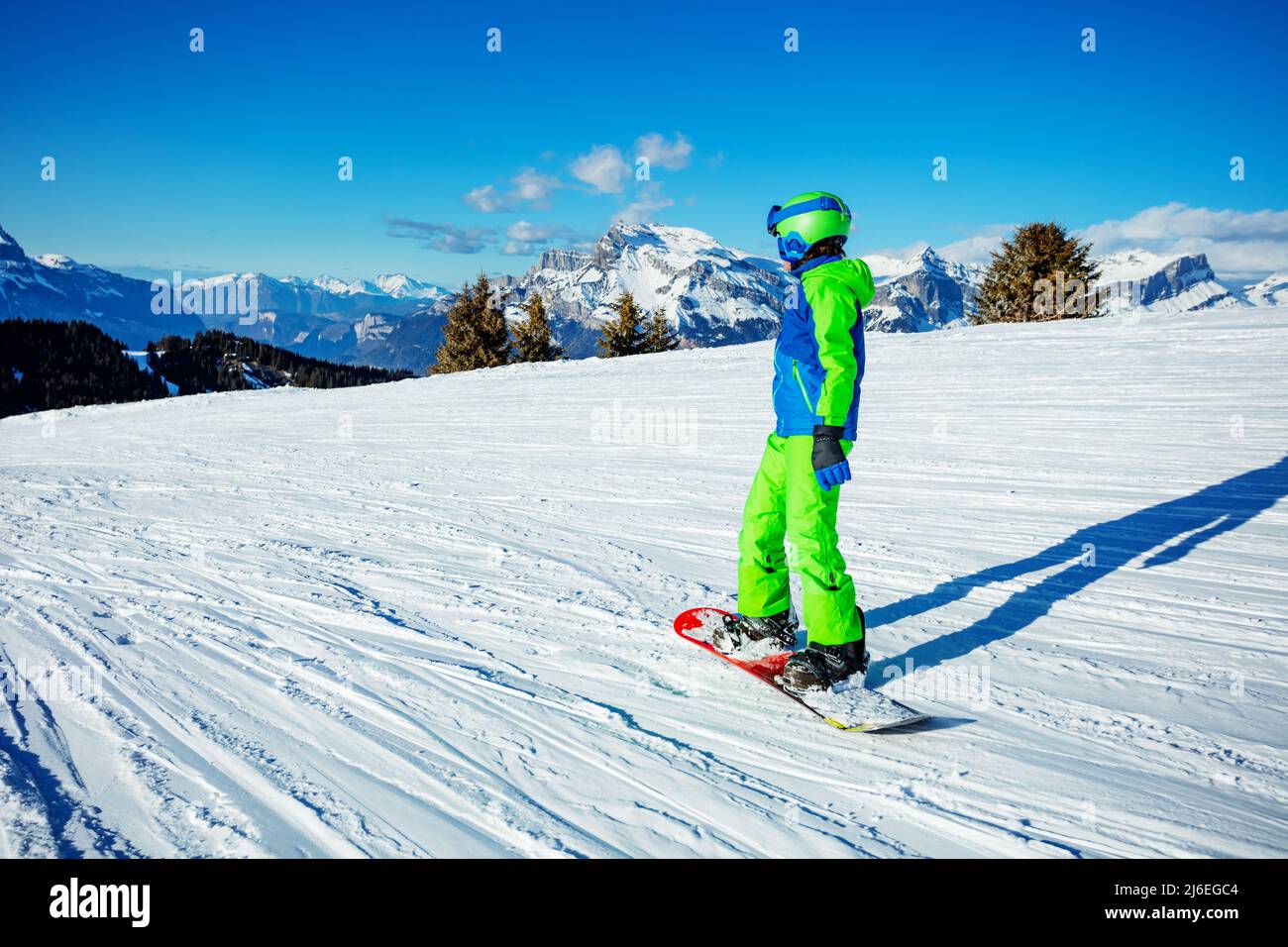 boy on snowboard go downhill with magnificent mountains behind Stock ...