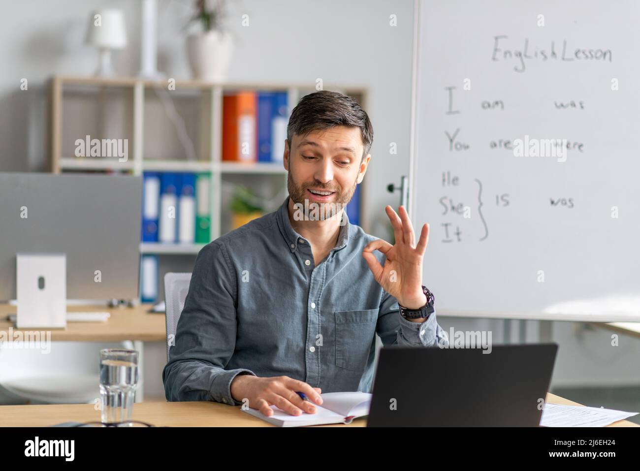 Cheerful male teacher giving online English lesson on laptop computer ...