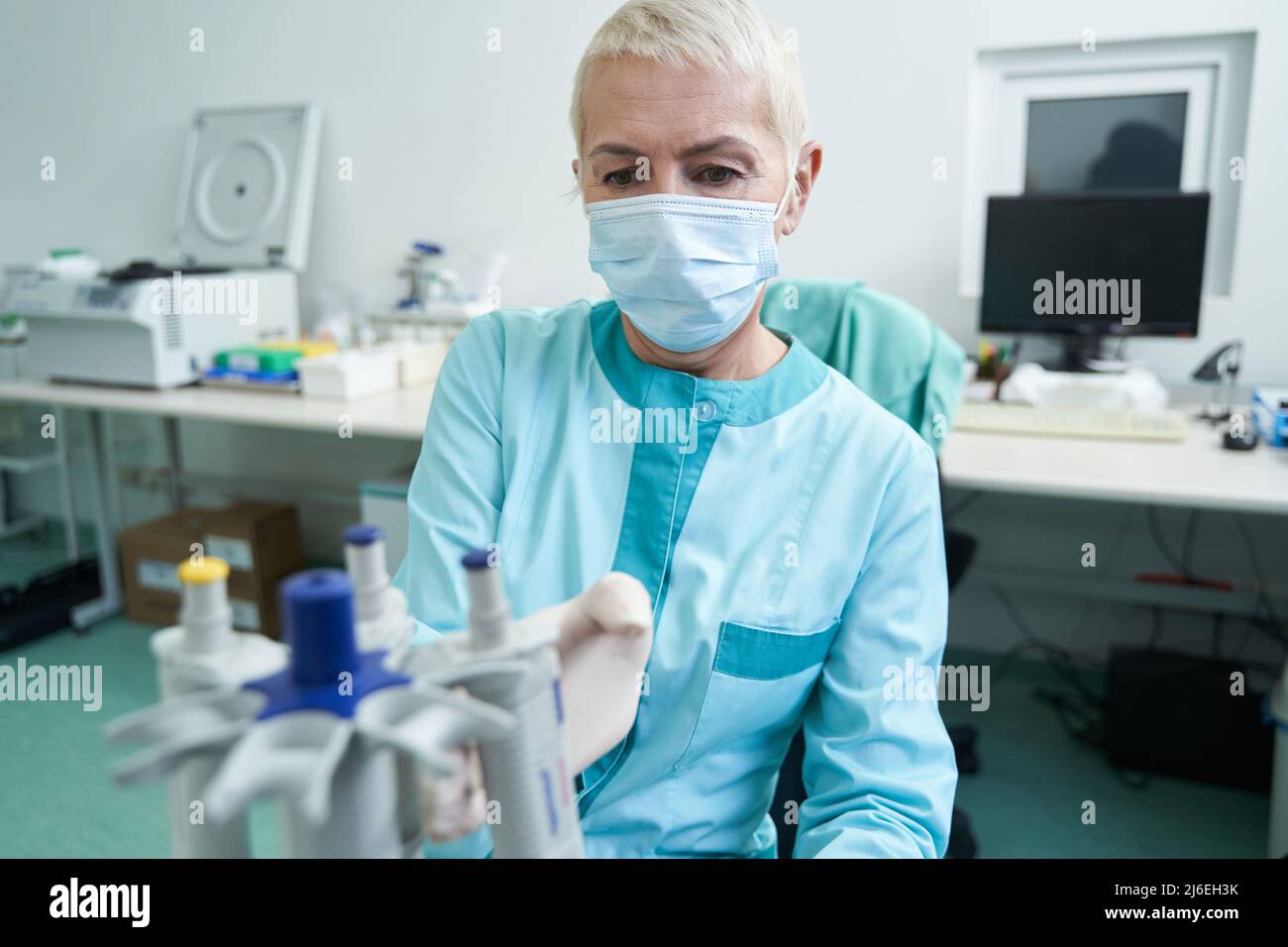 Woman in mask doing blood tests in laboratory Stock Photo - Alamy