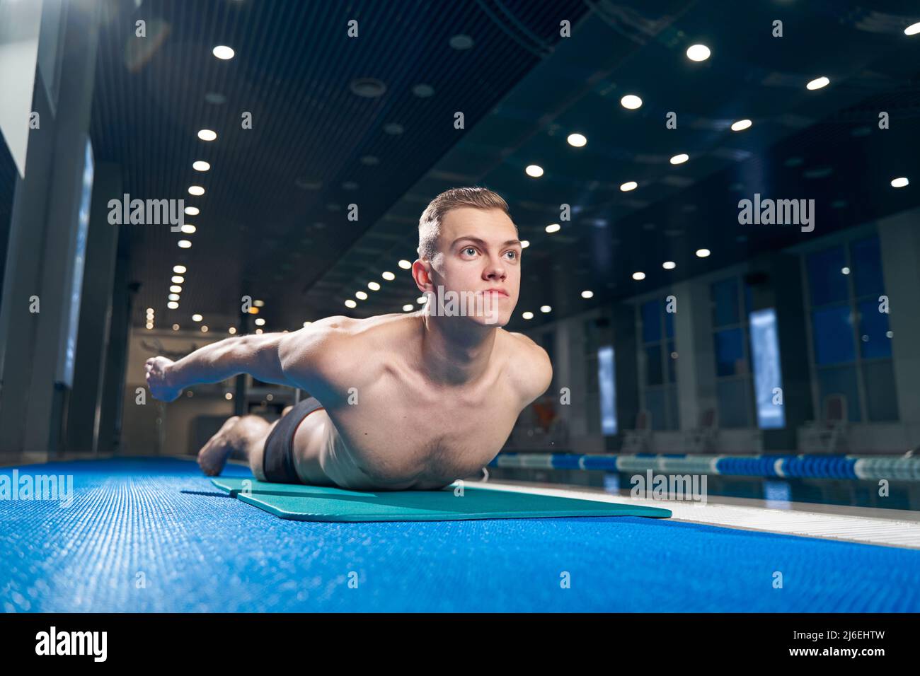 Athletic guy lying down on his stomach and spread his arms backward ...