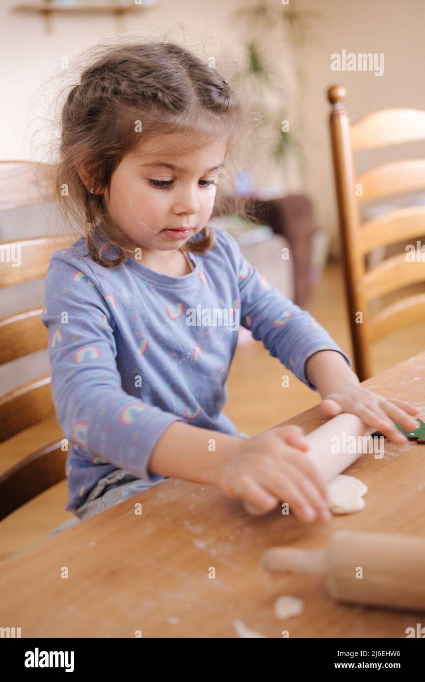 Little girl using rolling pin for making pizza at home. Close-up of ...
