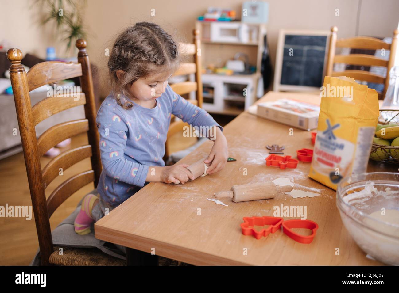 Little girl using rolling pin for making pizza at home. Close-up of ...
