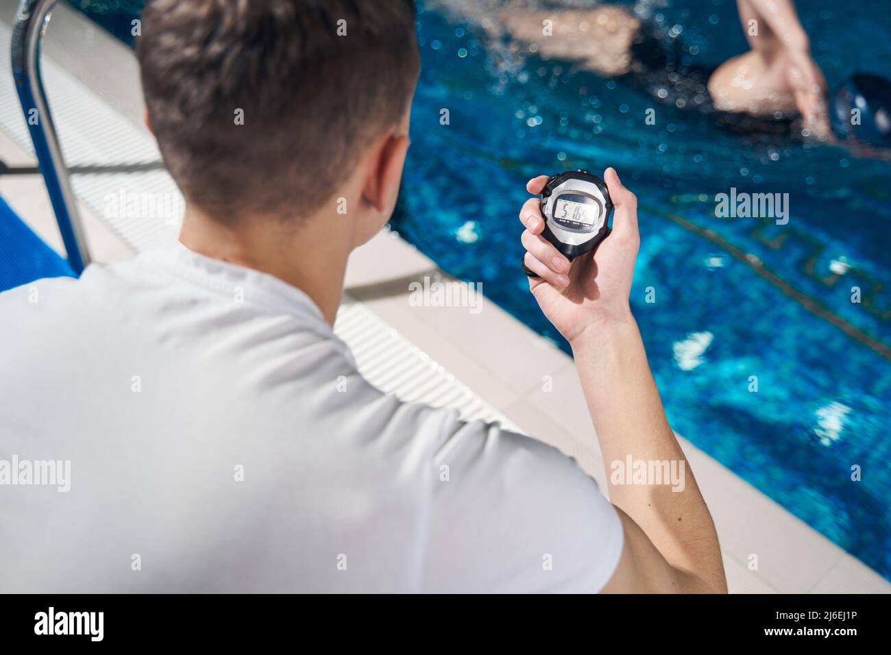 Male trainer looking on the timer during training Stock Photo - Alamy