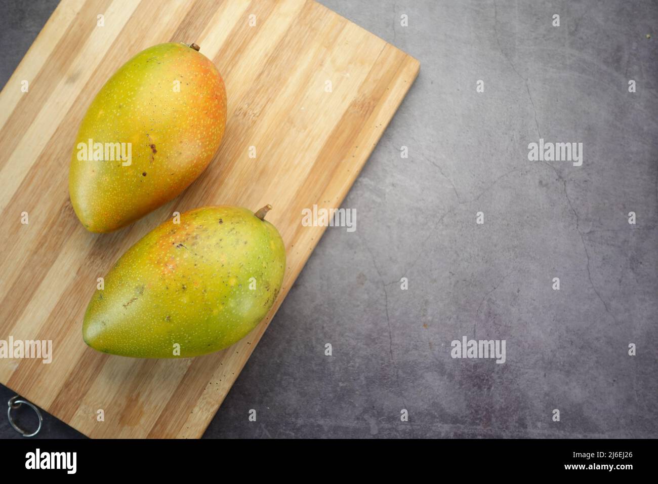 Fresh green mango on a chopping board on black Stock Photo - Alamy