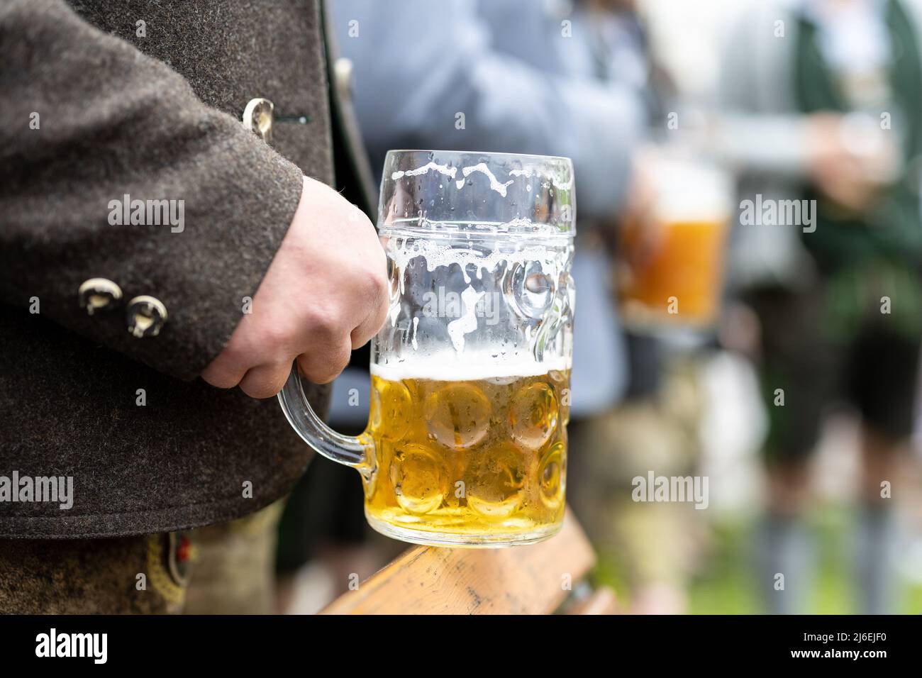 Perchting, Germany. 01st May, 2022. A man in traditional costume holds a half-full beer stein in ...