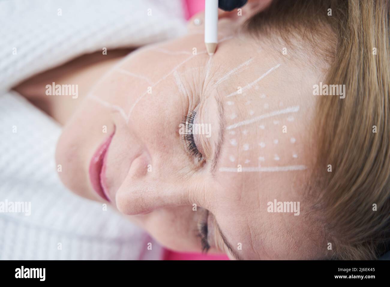Beautician drawing line on woman face with white pencil Stock Photo - Alamy