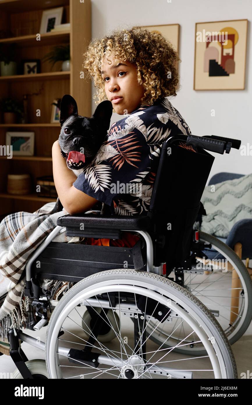African girl with disability sitting in wheelchair and embracing her ...