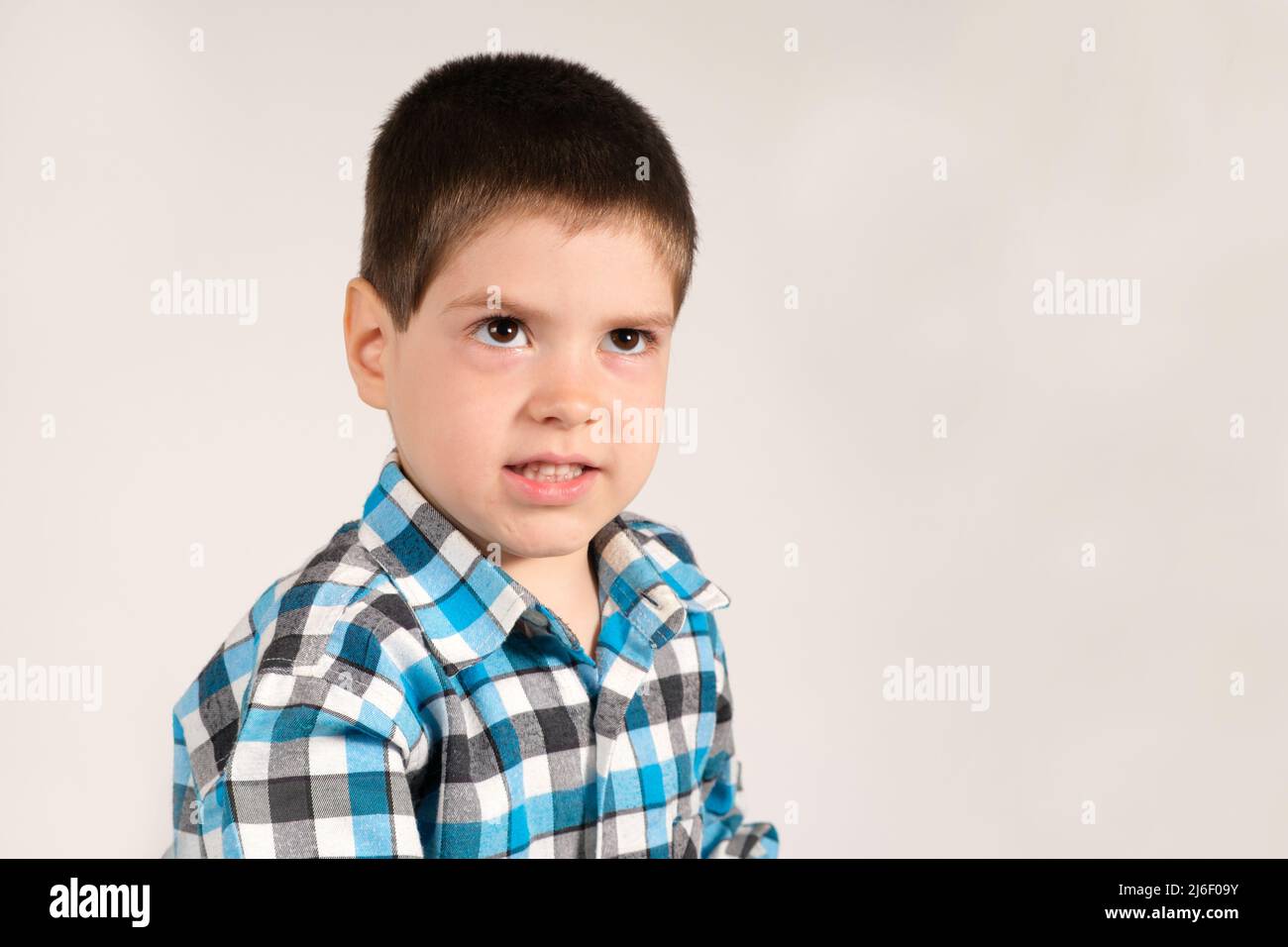 A 4-year-old preschool boy looks up belligerently, frowning his ...