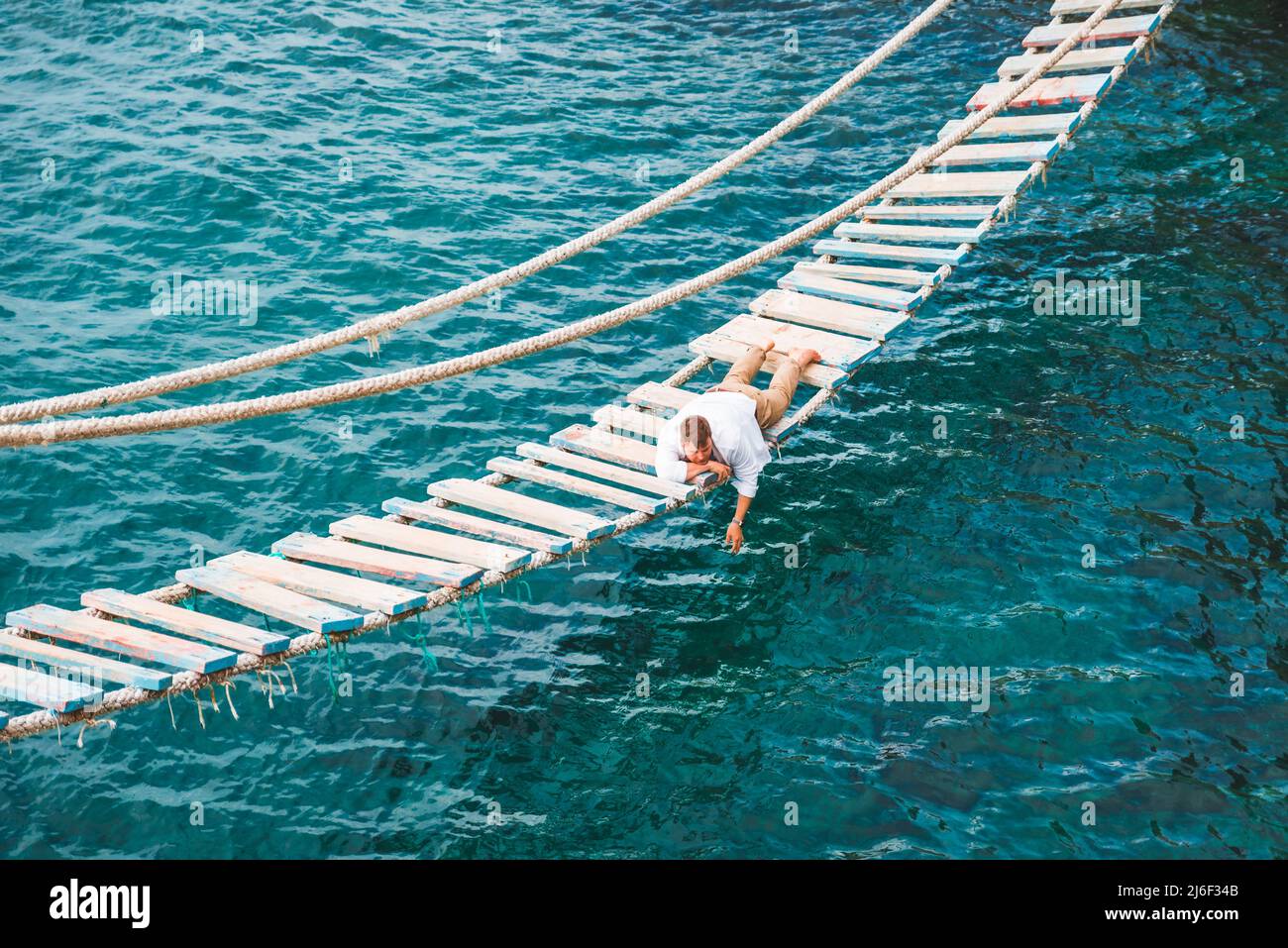 man laying at suspension bridge enjoying sea view and nature calmness ...
