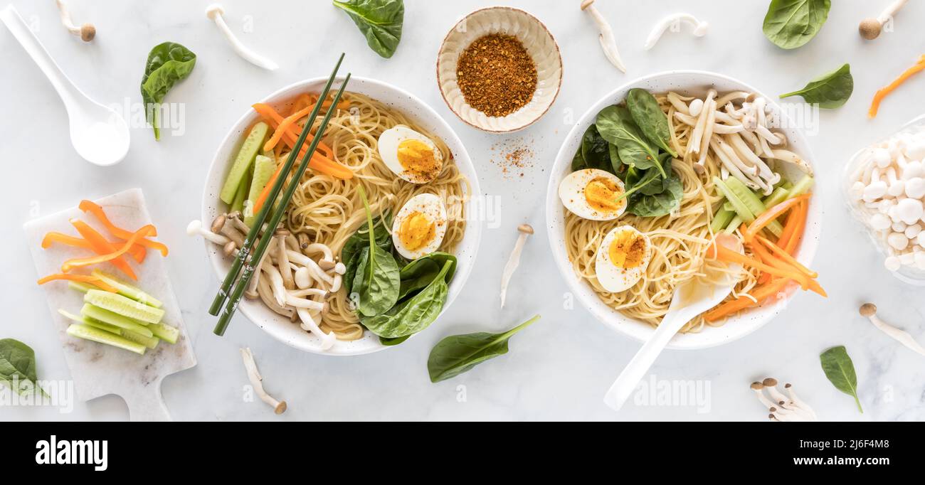 Top down view of bowls of Vietnamese Pho soup surrounded by ingredients ...