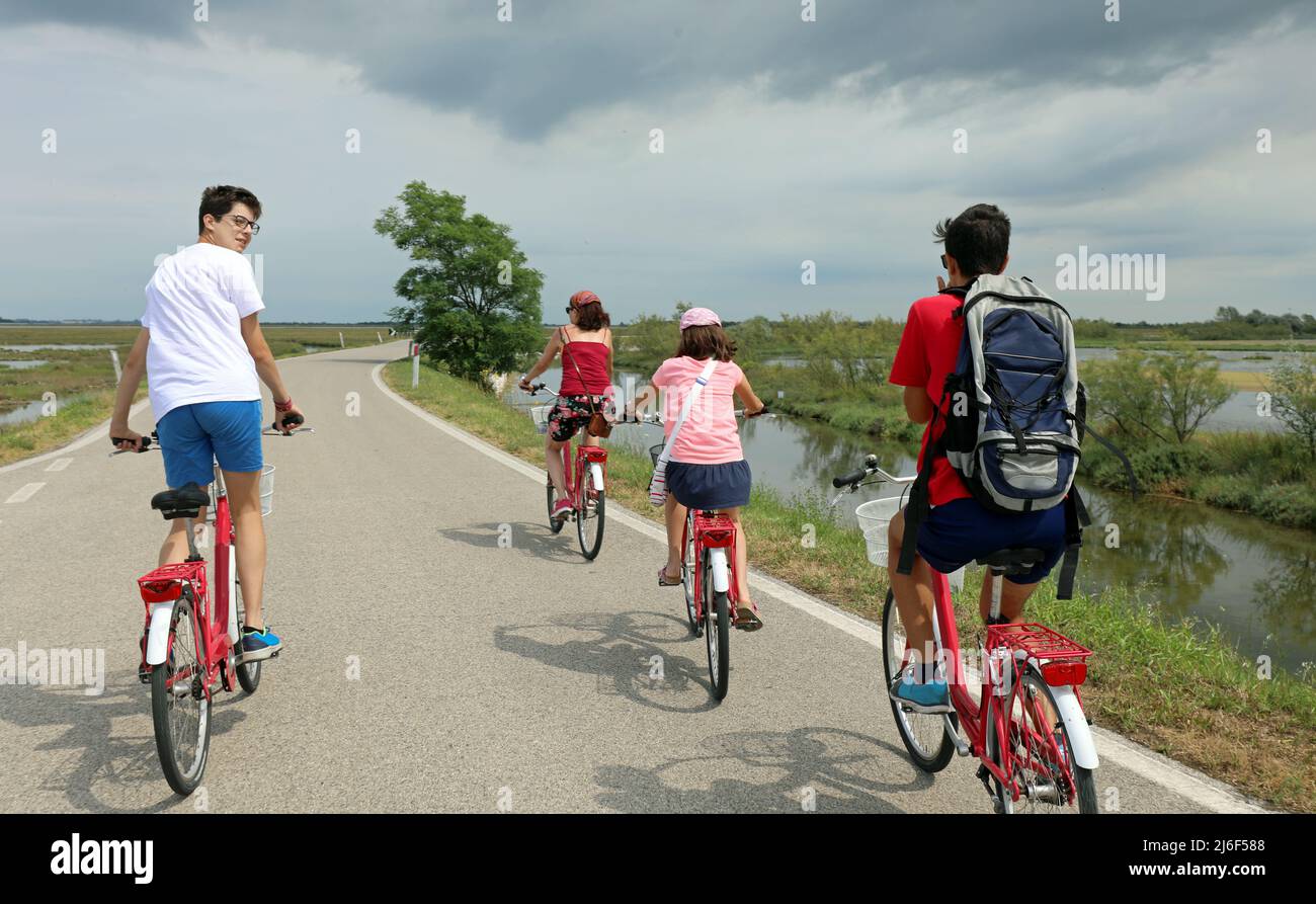 family of four during the bike ride on the bike path and the lagoon with brackish water Stock ...